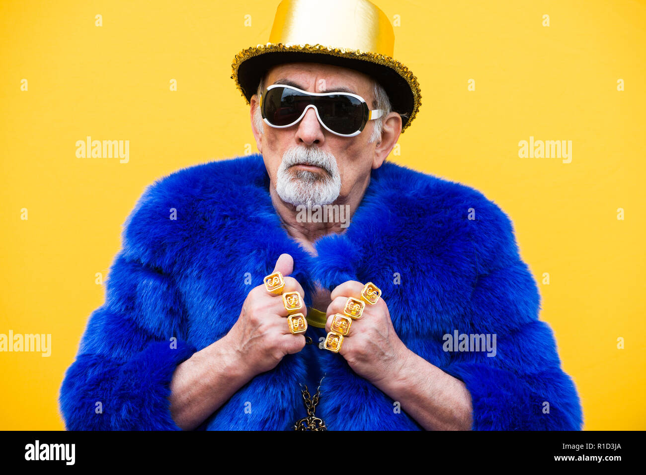 Funny and extravagant senior man posing on colored background ...