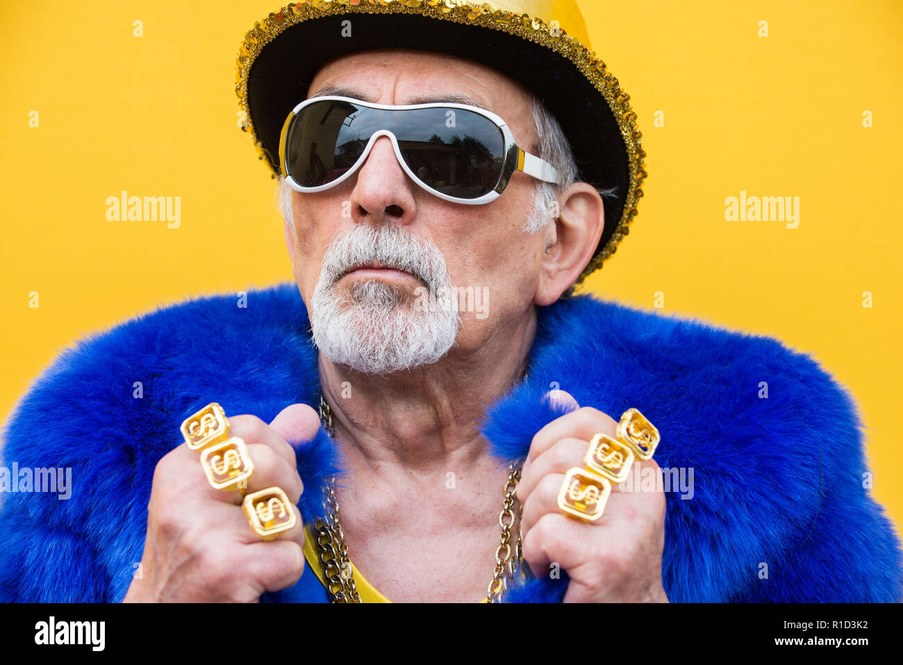 Funny and extravagant senior man posing on colored background ...