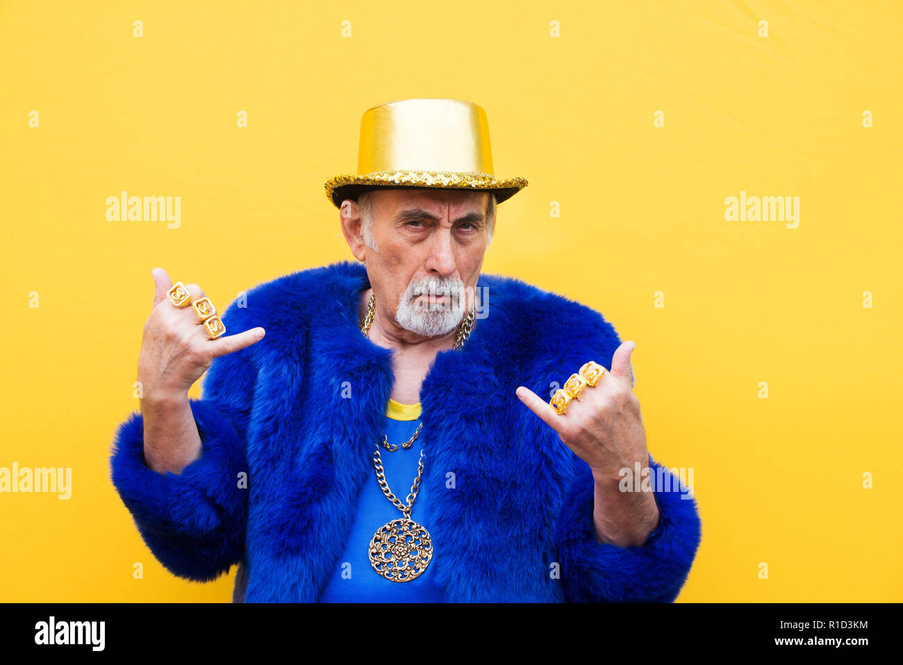 Funny and extravagant senior man posing on colored background ...