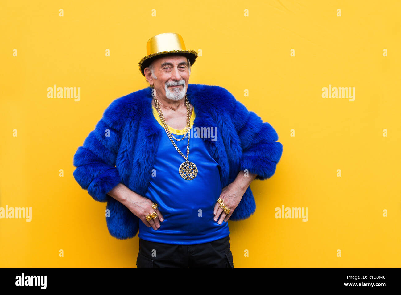 Funny and extravagant senior man posing on colored background ...