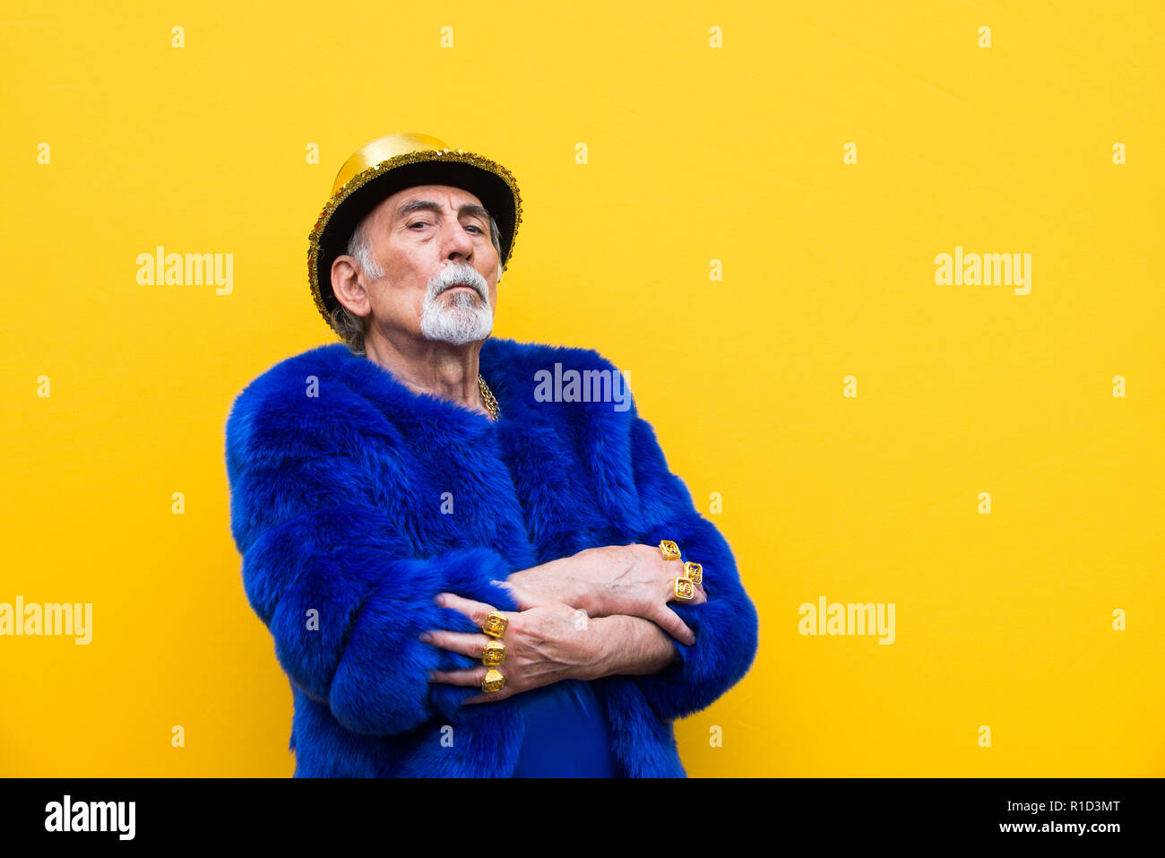 Funny and extravagant senior man posing on colored background ...