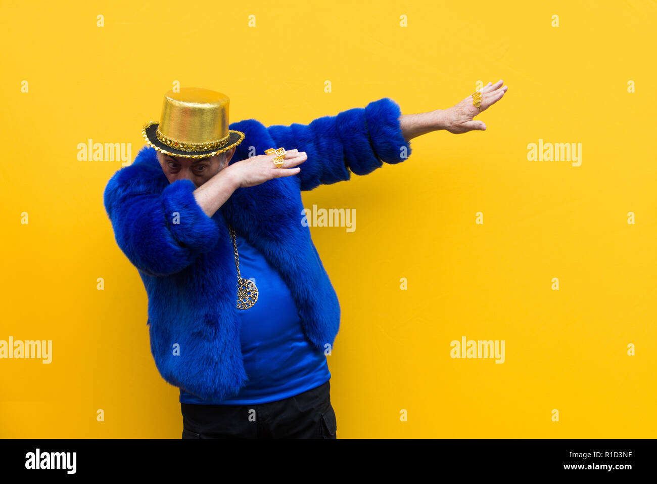 Funny and extravagant senior man posing on colored background ...