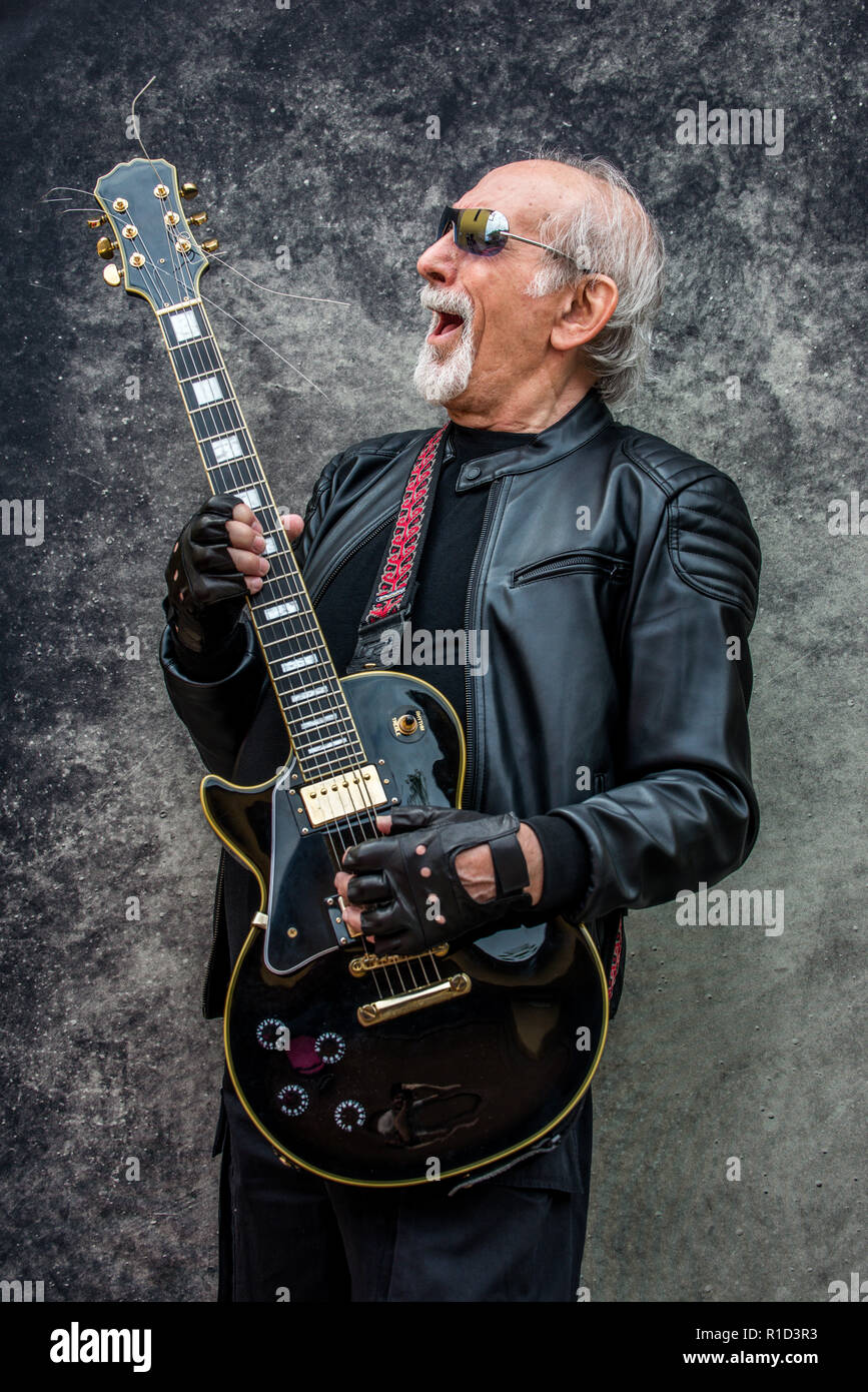 Funny and extravagant senior man posing on colored background ...