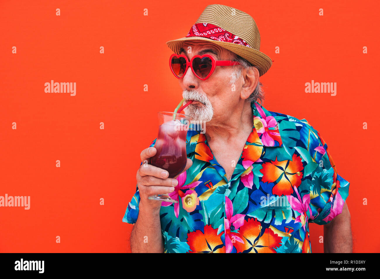 Funny and extravagant senior man posing on colored background ...