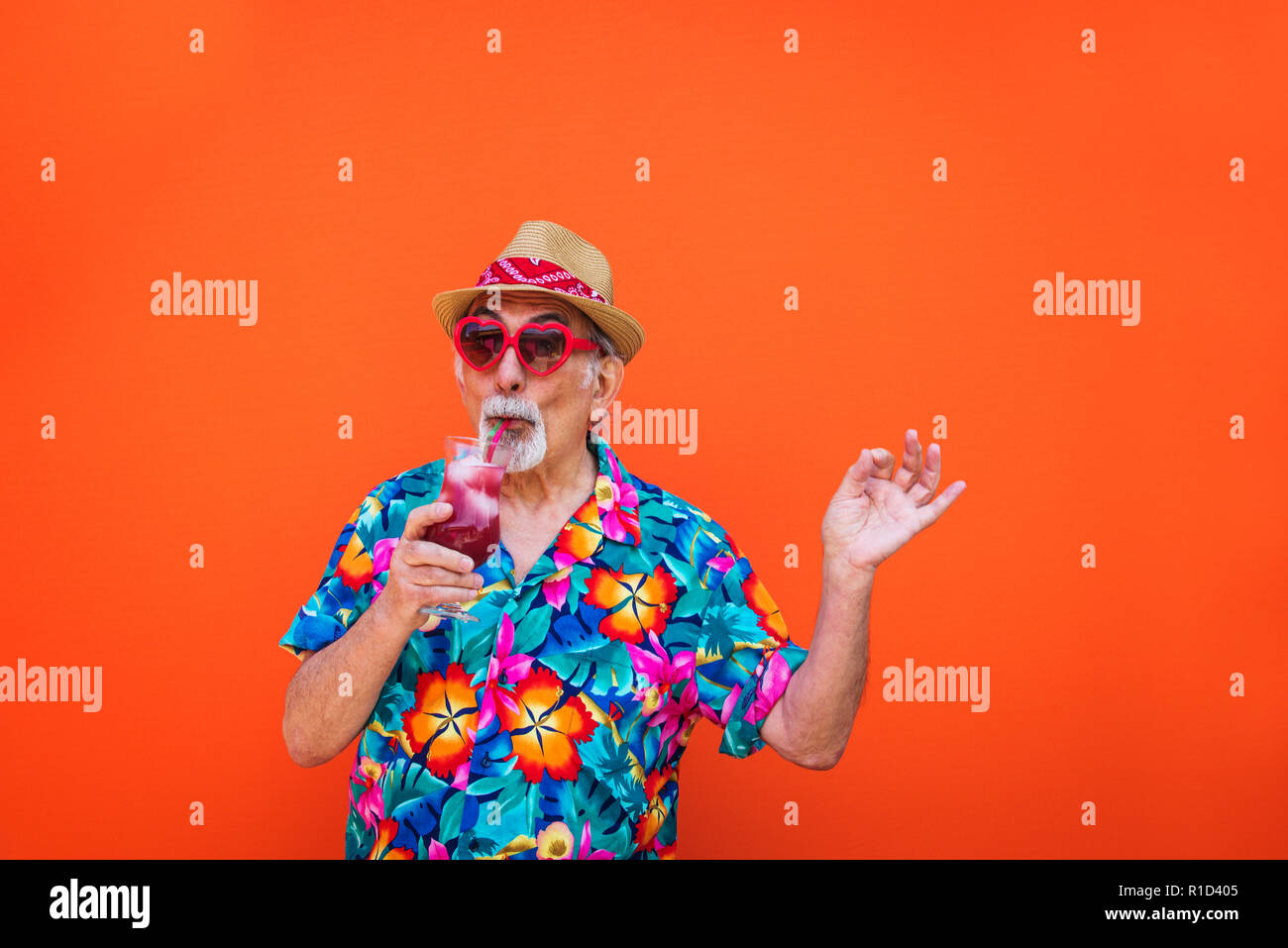 Funny and extravagant senior man posing on colored background ...