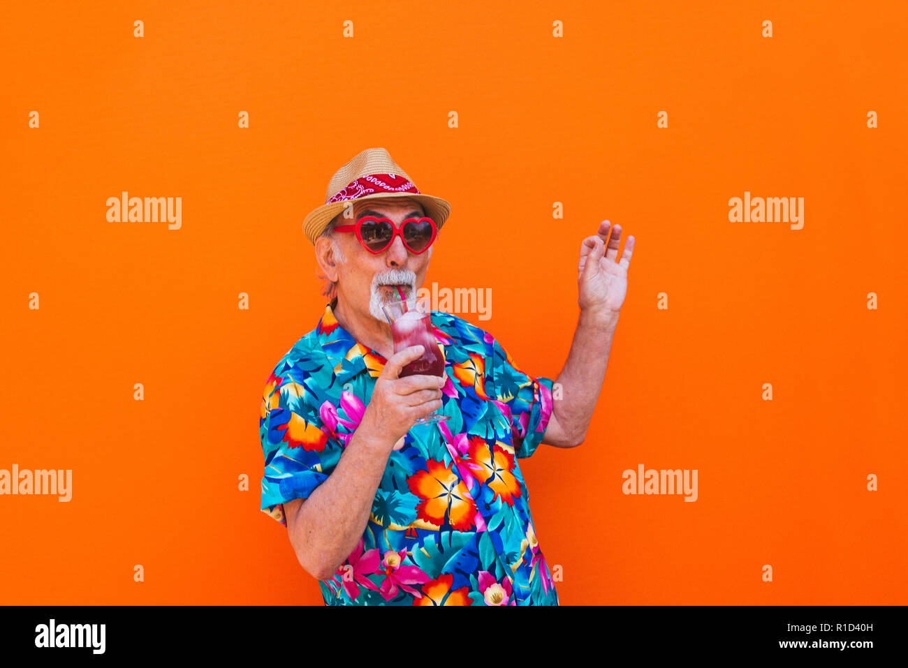Funny and extravagant senior man posing on colored background ...
