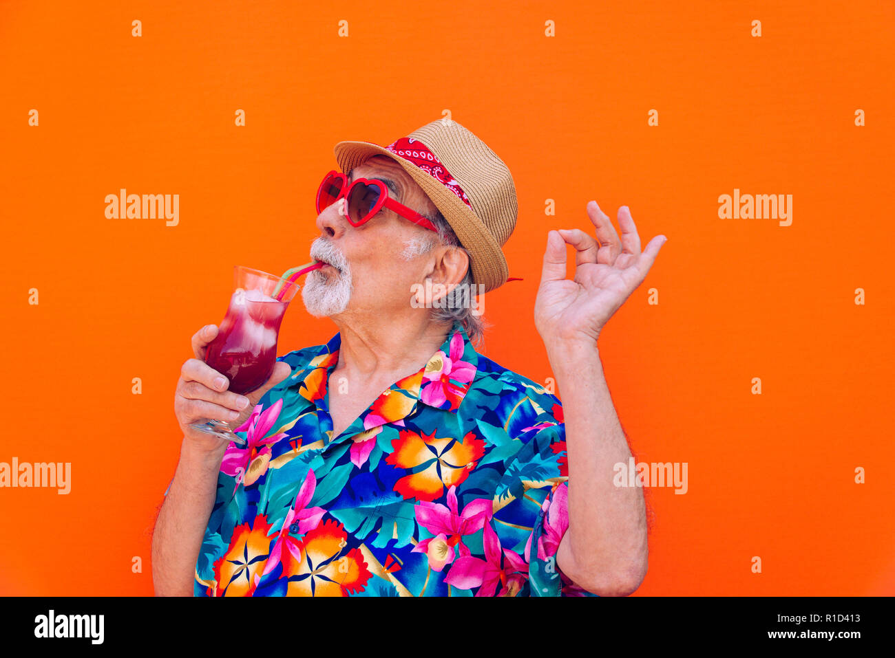 Funny and extravagant senior man posing on colored background ...
