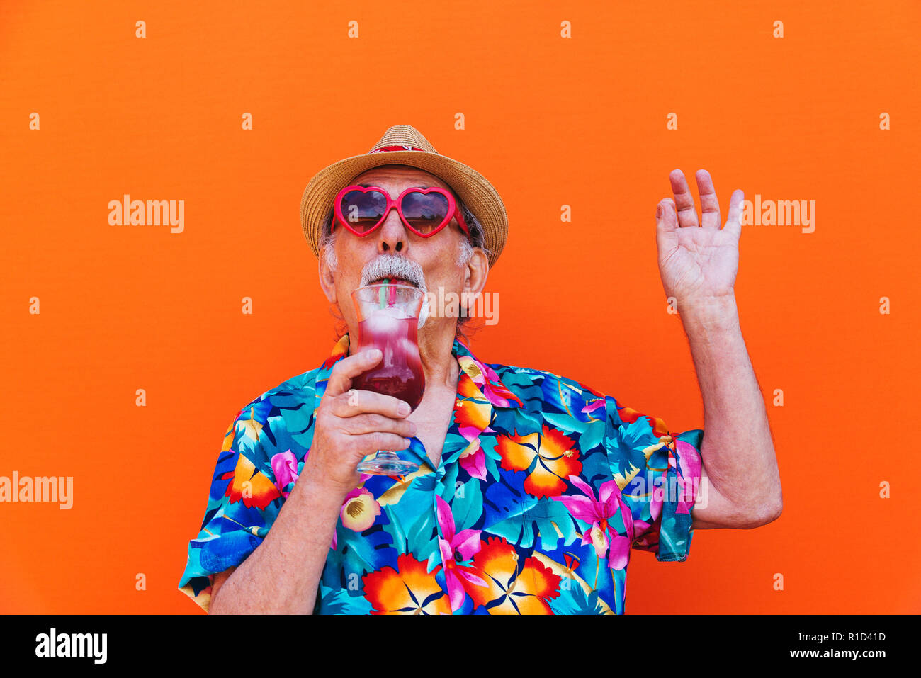 Funny and extravagant senior man posing on colored background ...
