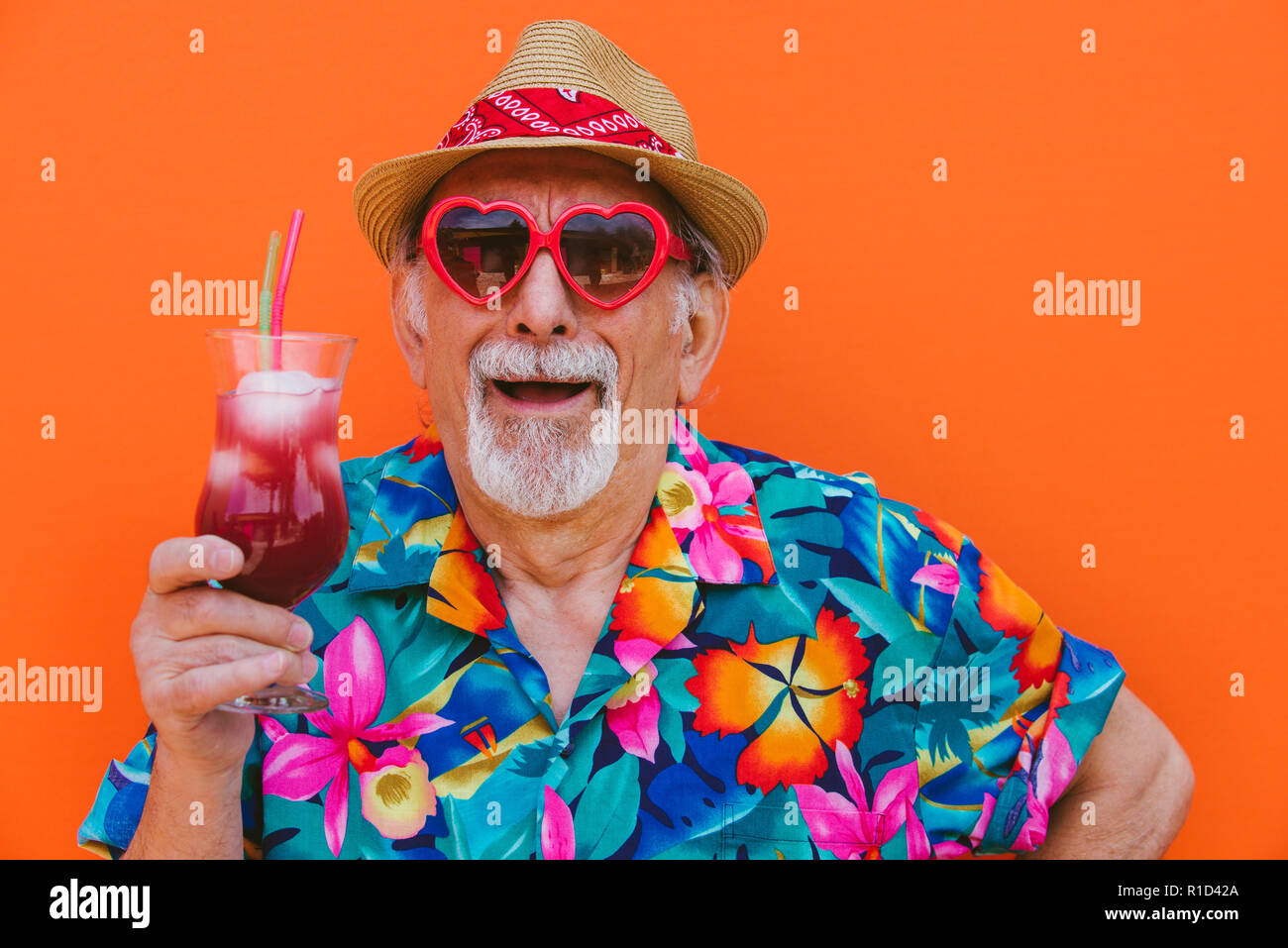 Funny and extravagant senior man posing on colored background ...