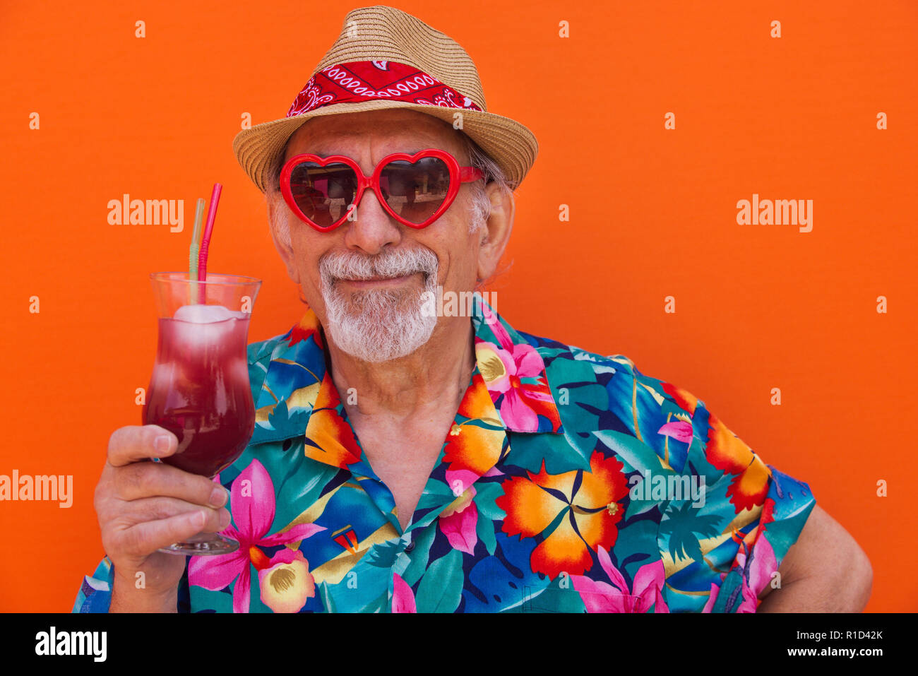 Funny and extravagant senior man posing on colored background ...