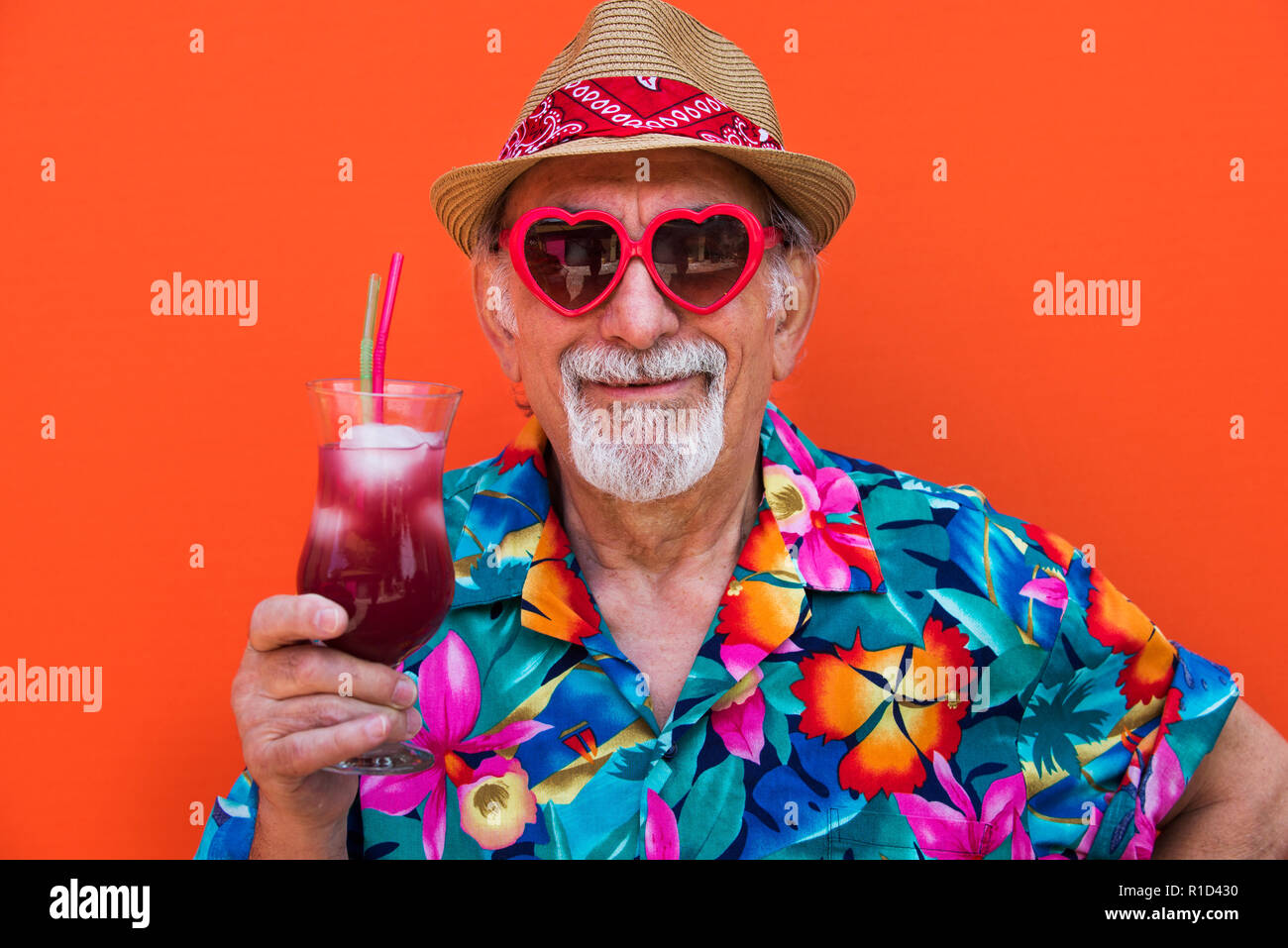 Funny and extravagant senior man posing on colored background ...