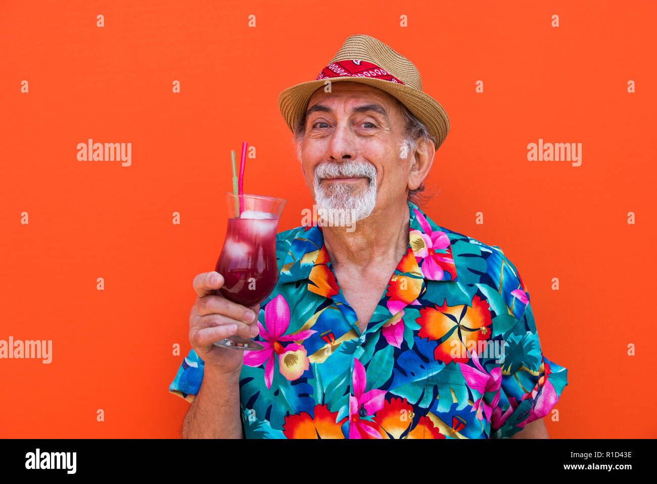 Funny and extravagant senior man posing on colored background ...