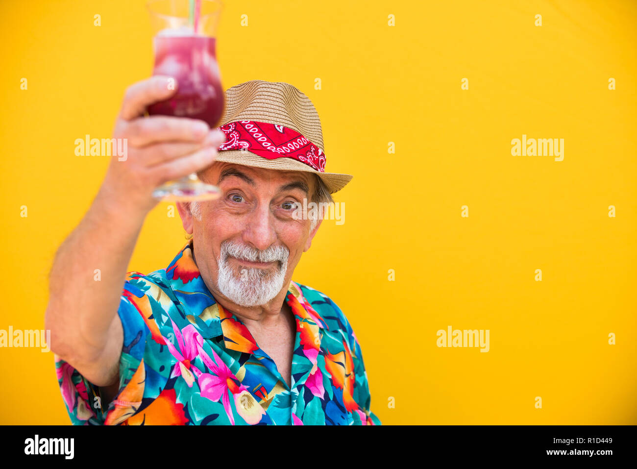 Funny and extravagant senior man posing on colored background ...