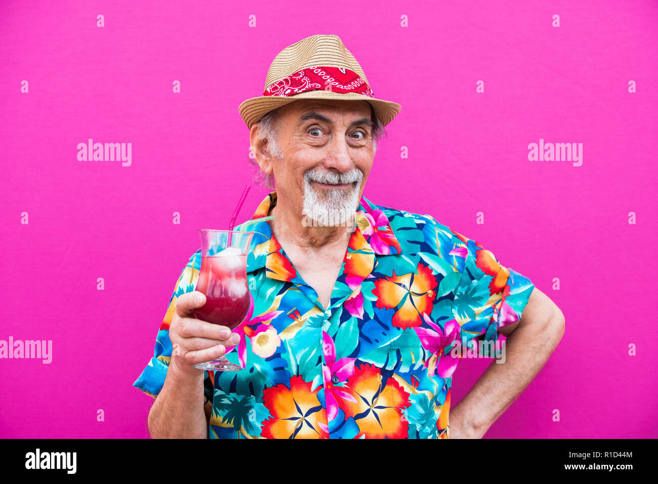 Funny and extravagant senior man posing on colored background ...