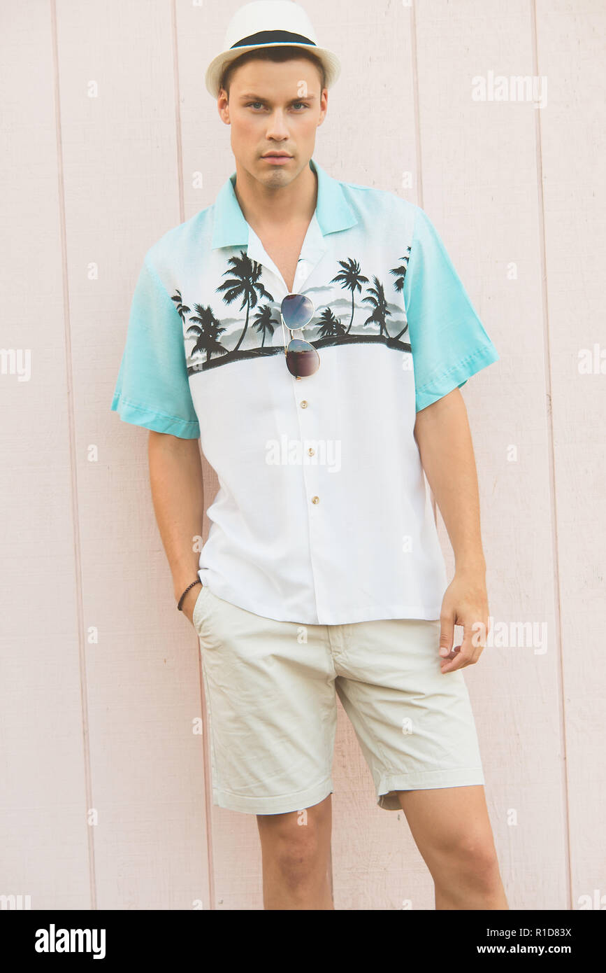 A handsome male model posing in Summer Clothes outdoor against a plain ...