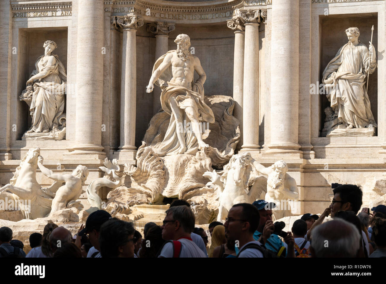 Statues on the Trevi Fountain look down on hordes of visiting tourists ...