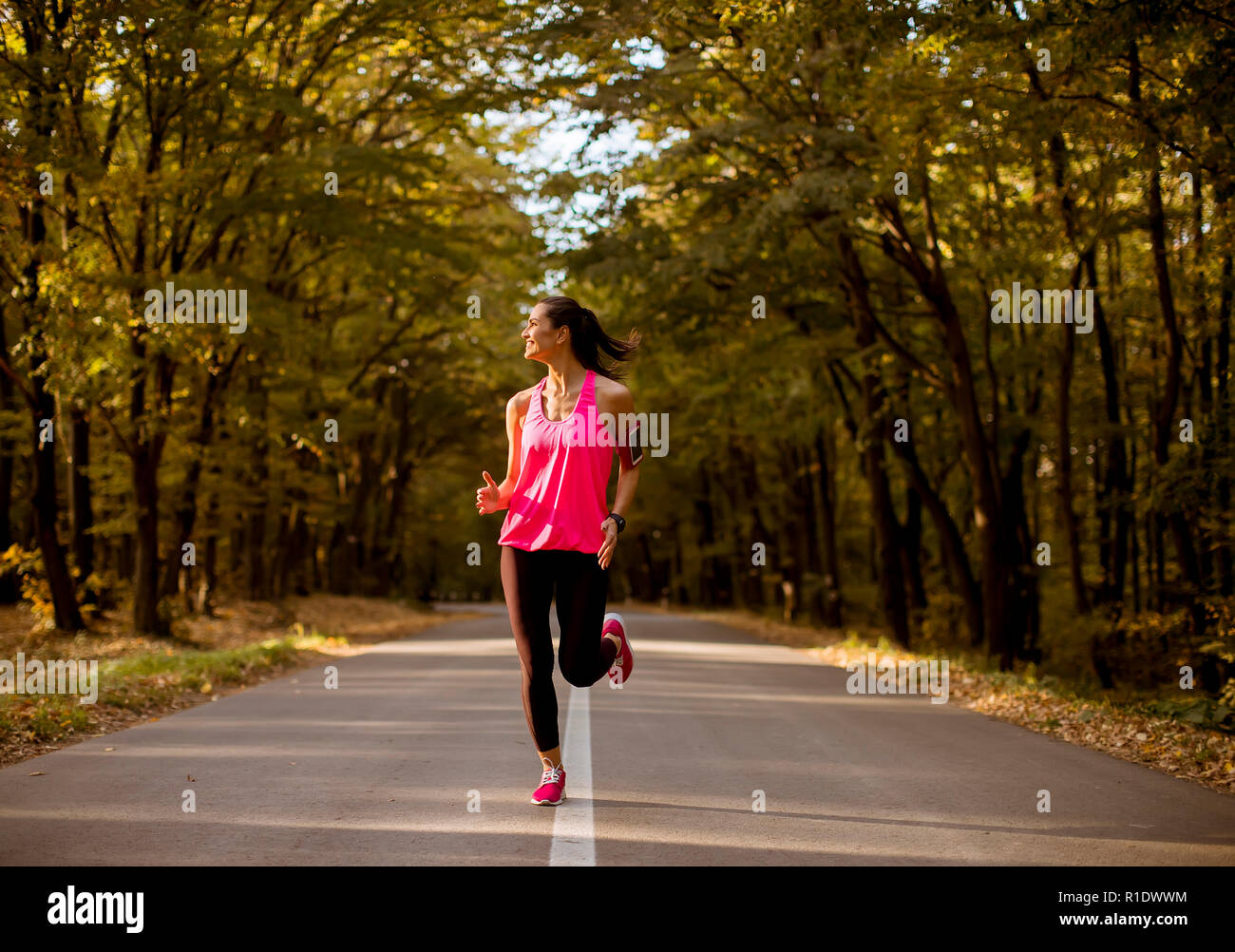 Young fitness woman running at forest trail in golden autumn Stock ...