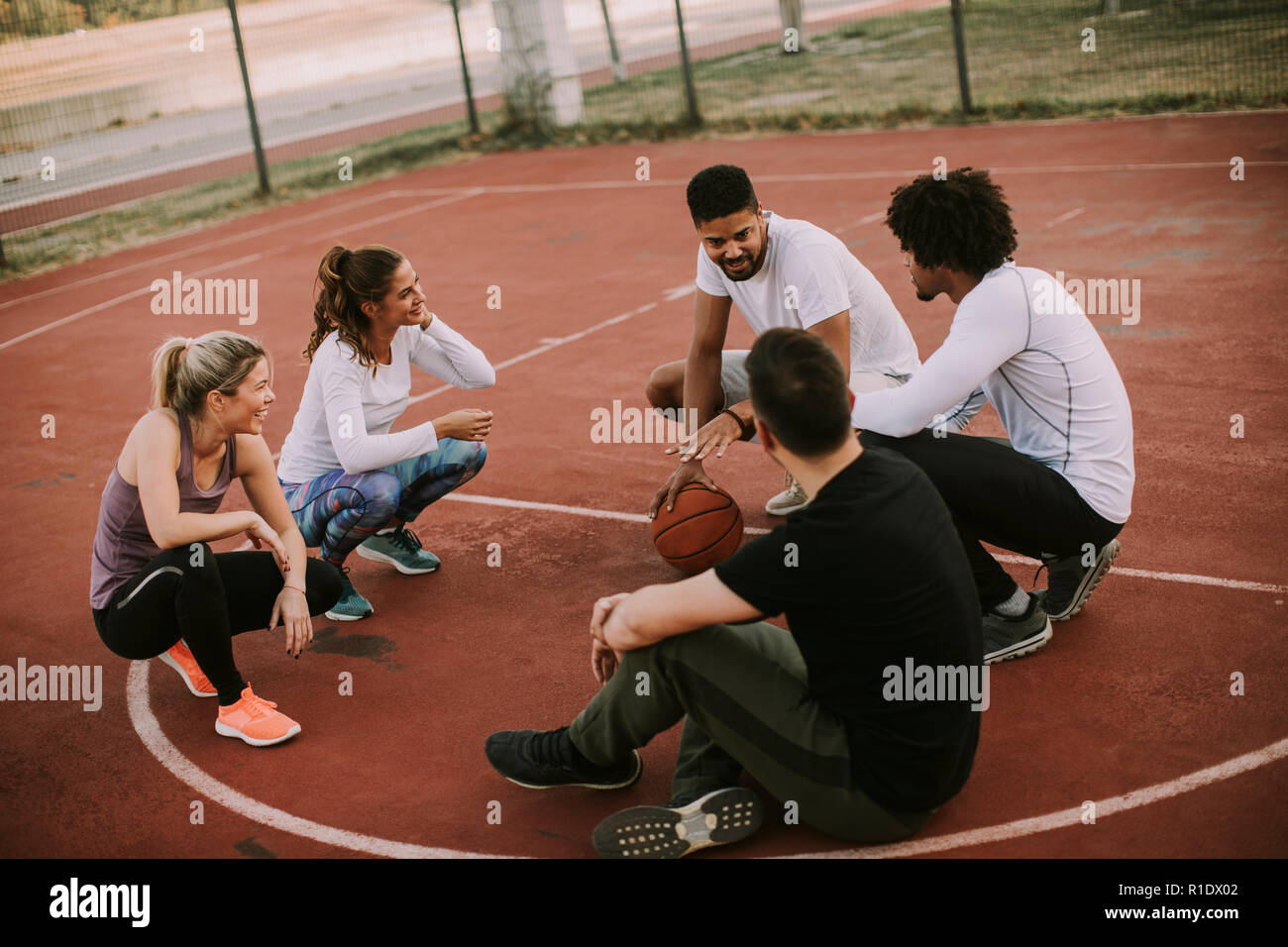 Multiethnic group of basketball players resting on court together Stock ...