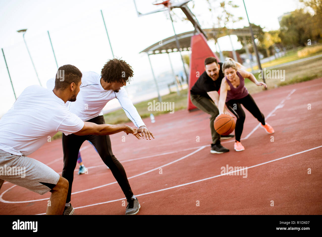 Group of multiethnic young people playing basketball on court Stock ...