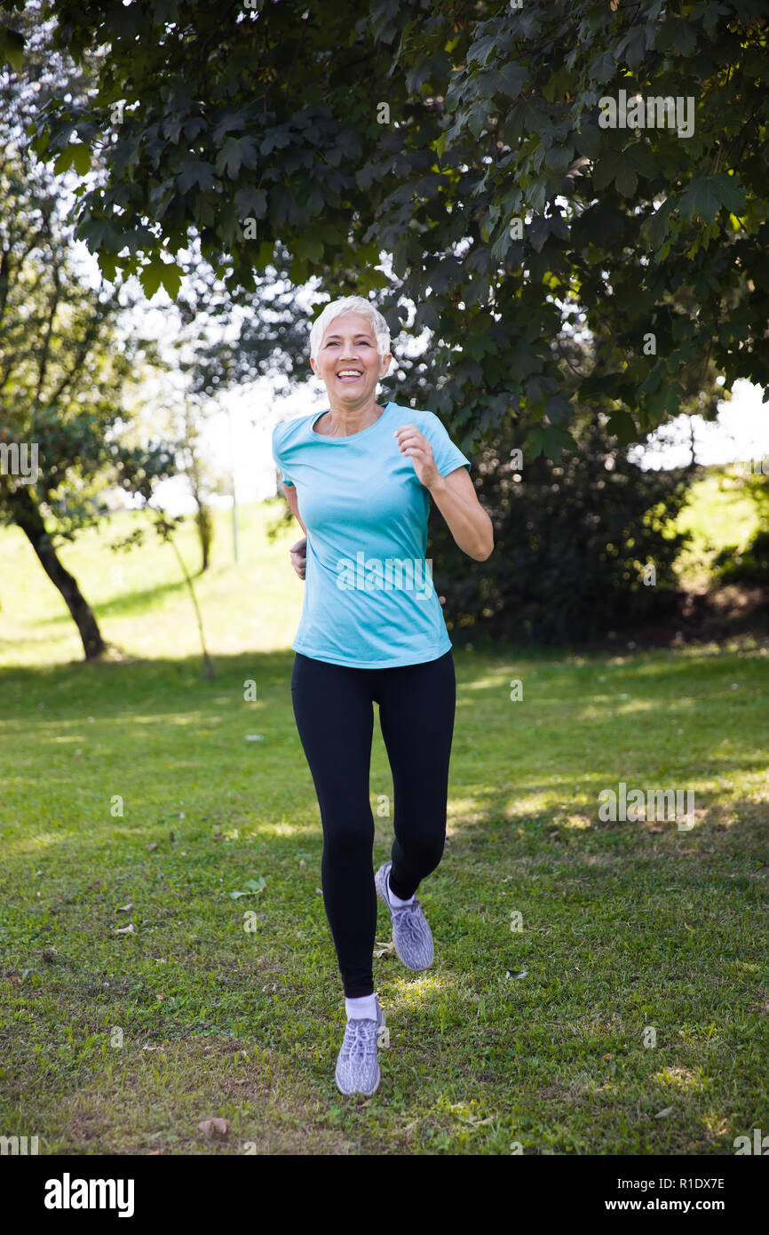 Front view of senior woman jogging through park Stock Photo - Alamy