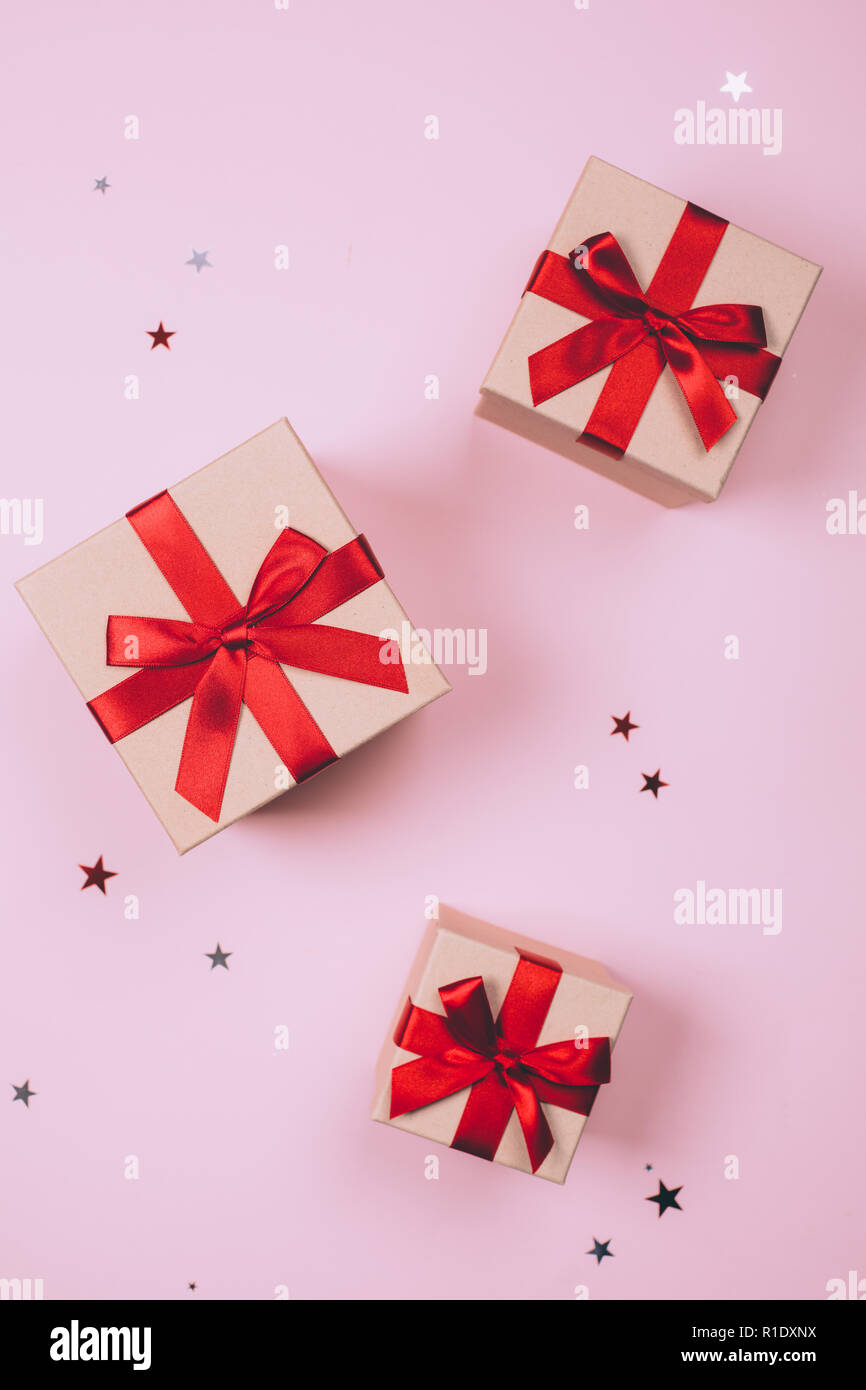 Three presents with red bow on pastel trendy pink background with ...