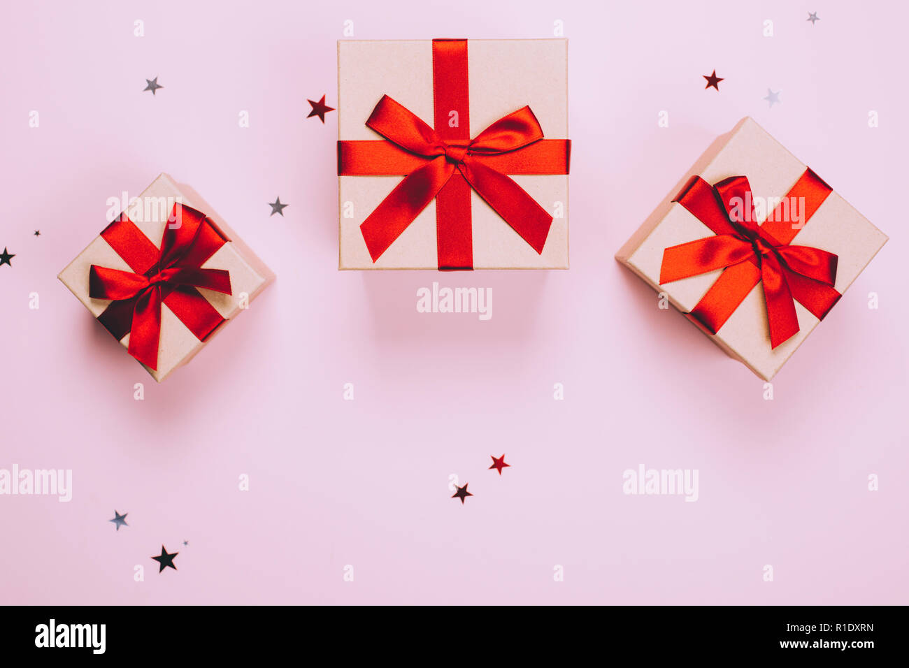 Three presents with red bow on pastel trendy pink background with ...