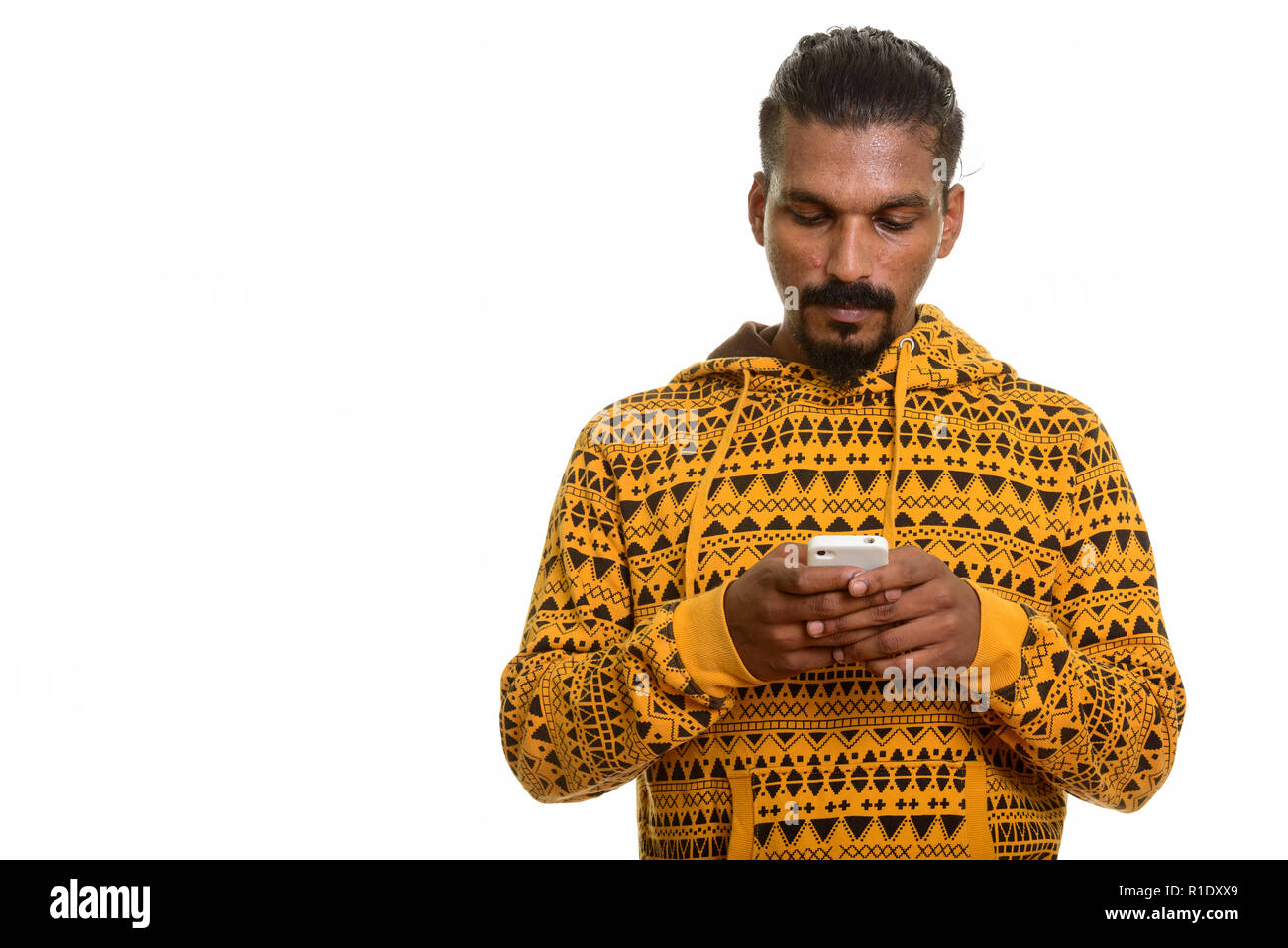 Young Indian man using mobile phone studio portrait against white ...