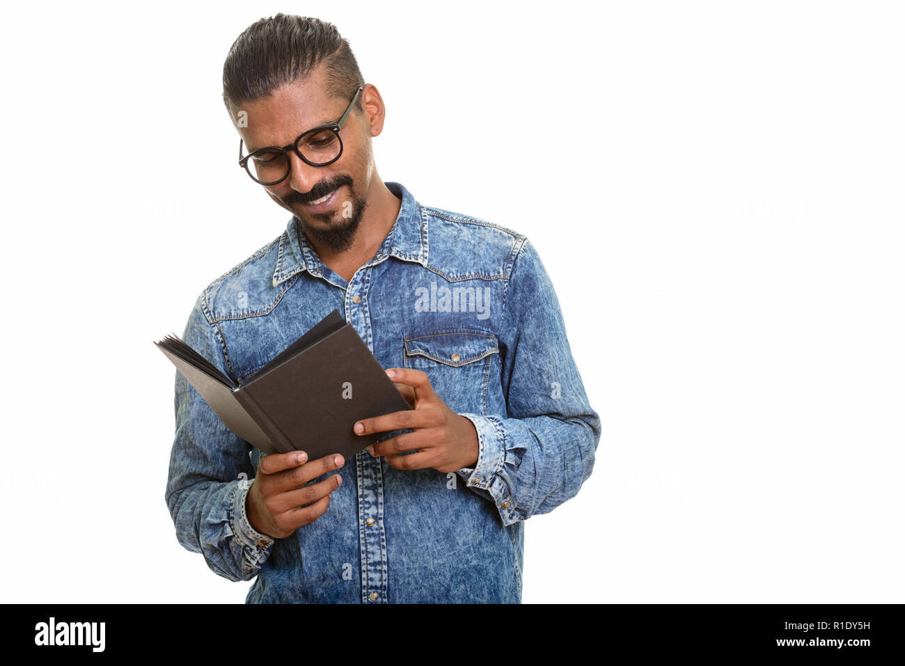Young happy Indian man reading book studio portrait against white ...