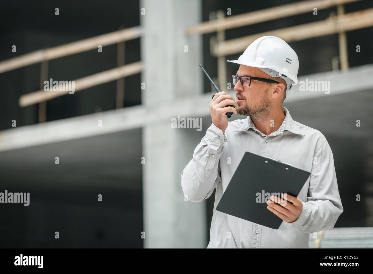 Male head engineer wearing white safety hardhat with walkie talkie and ...
