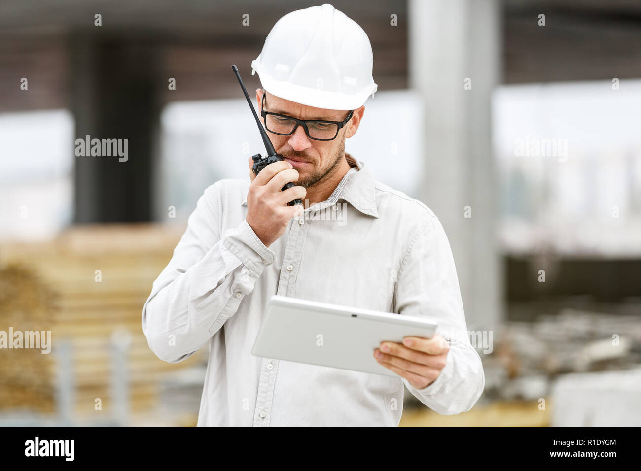 Male head engineer wearing white safety hardhat with walkie talkie and ...