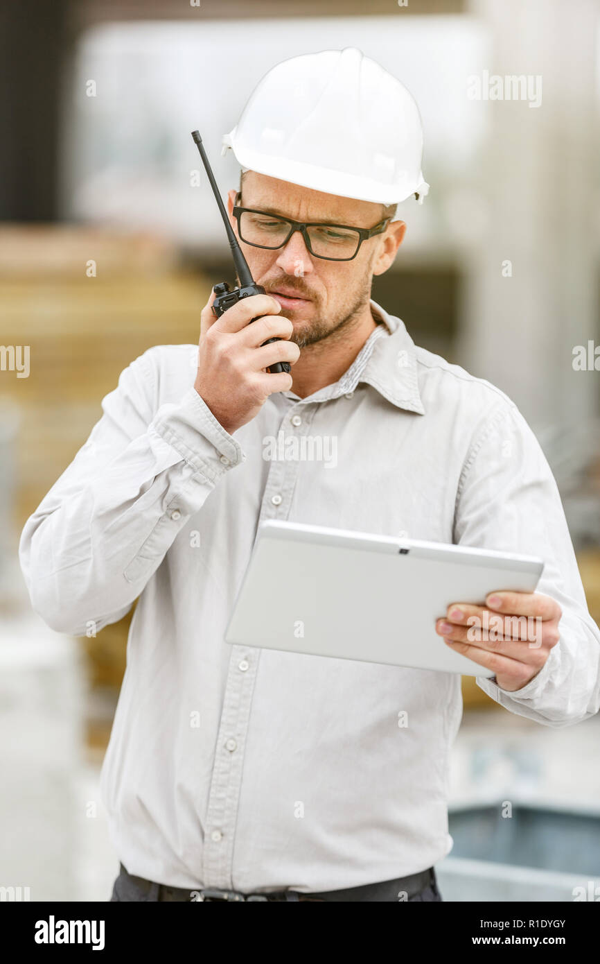 Male head engineer wearing white safety hardhat with walkie talkie and ...