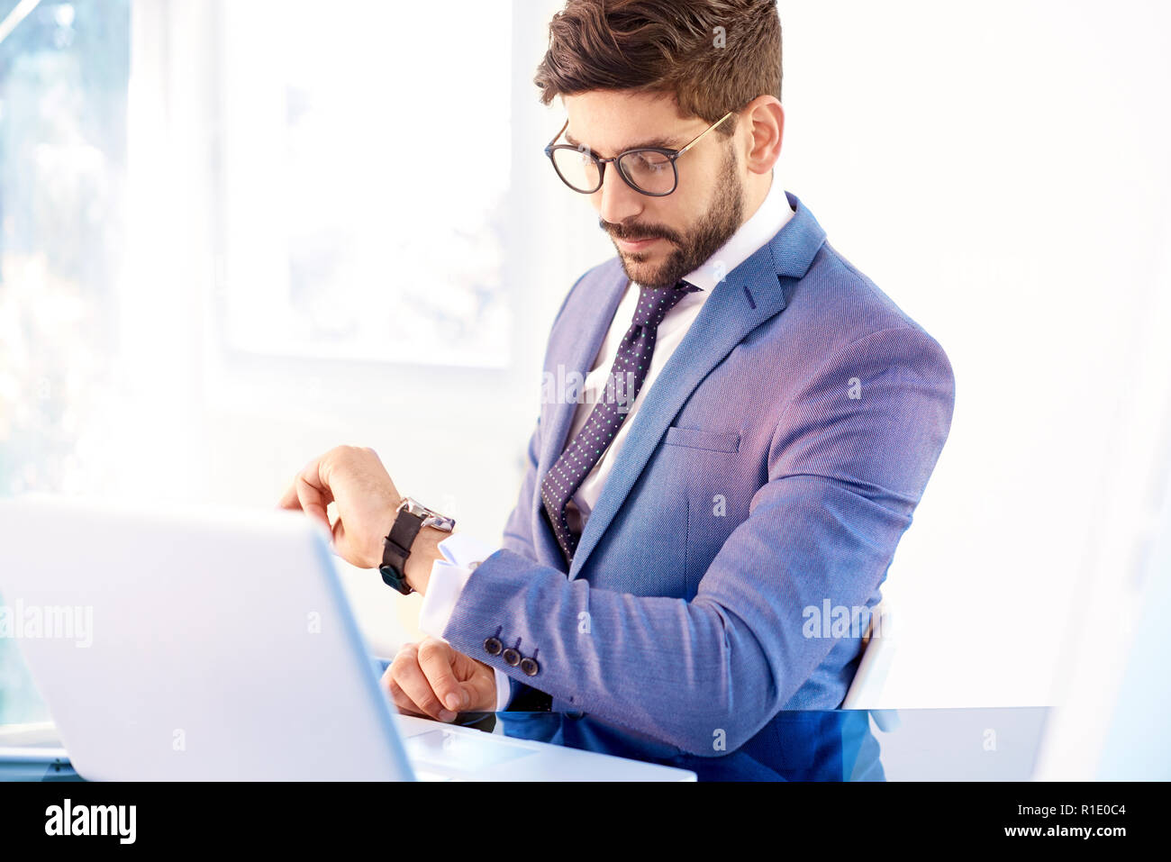 Shot of young businessman checking the time on his wristwatch while ...