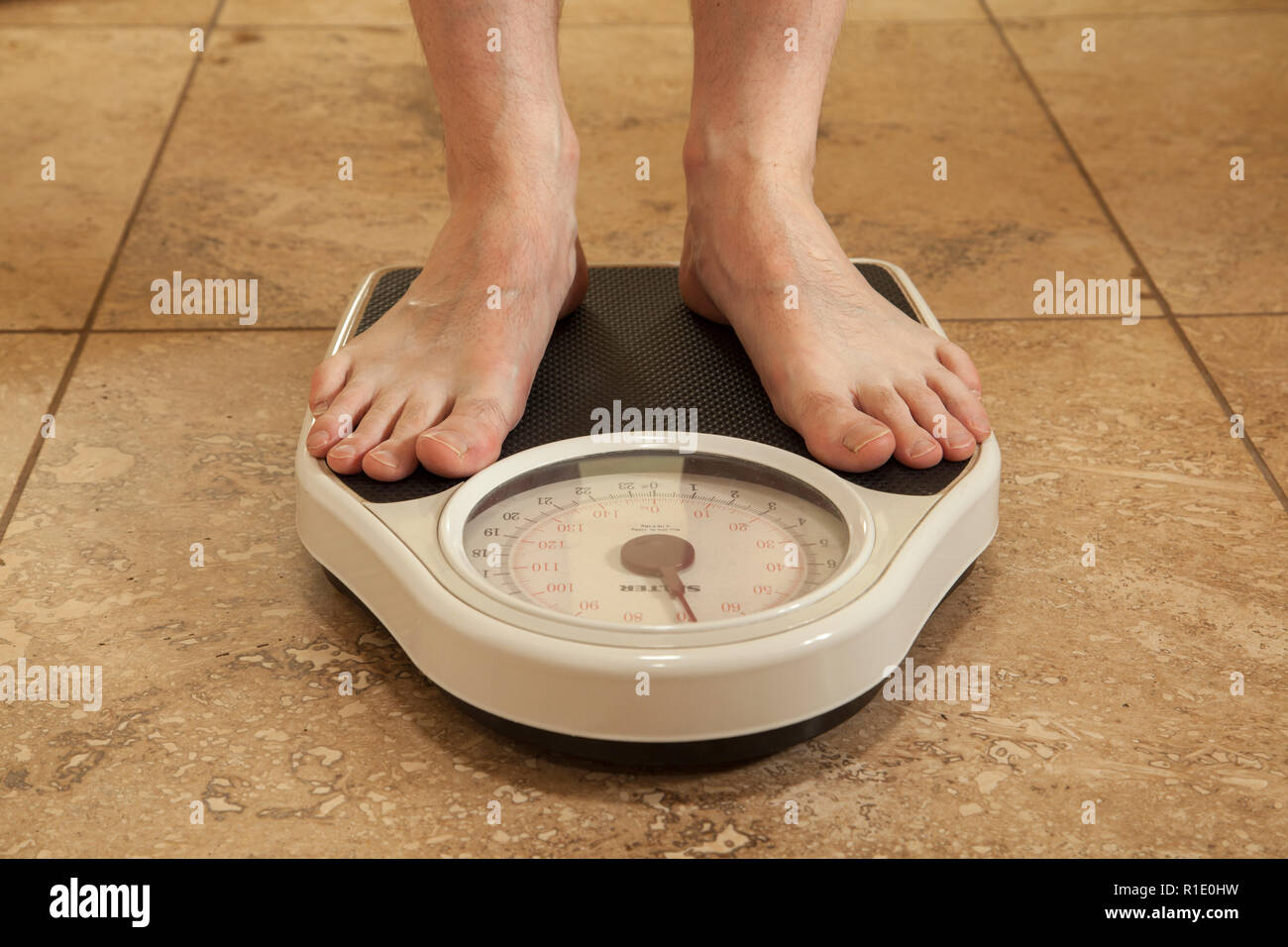 Man standing on bathroom scales Stock Photo - Alamy