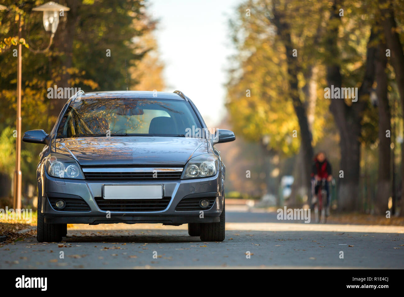 Front view of gray shiny empty car parked in quiet area on asphalt road ...