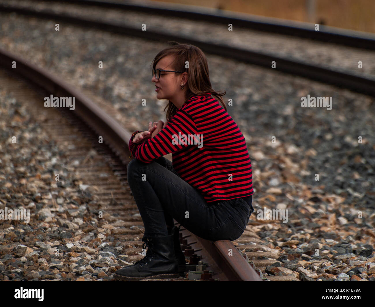 A lonely teen girl sitting on the train tracks Stock Photo - Alamy