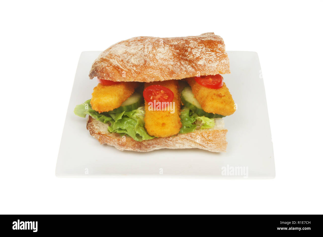 Fishfingers and salad in a ciabatta roll on a plate isolated against ...