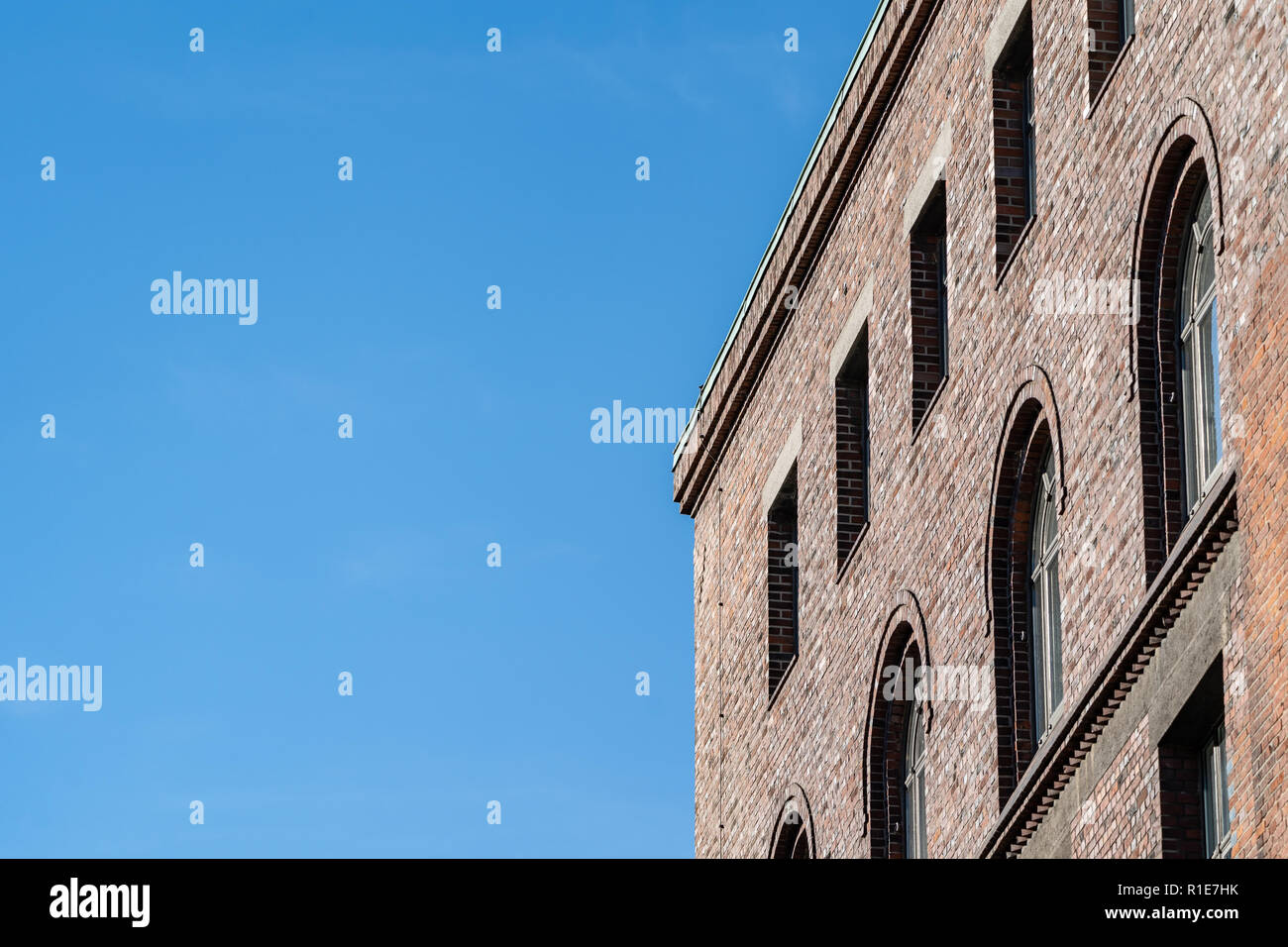 Top corner of brick building facade with arched windows, viewed from ...