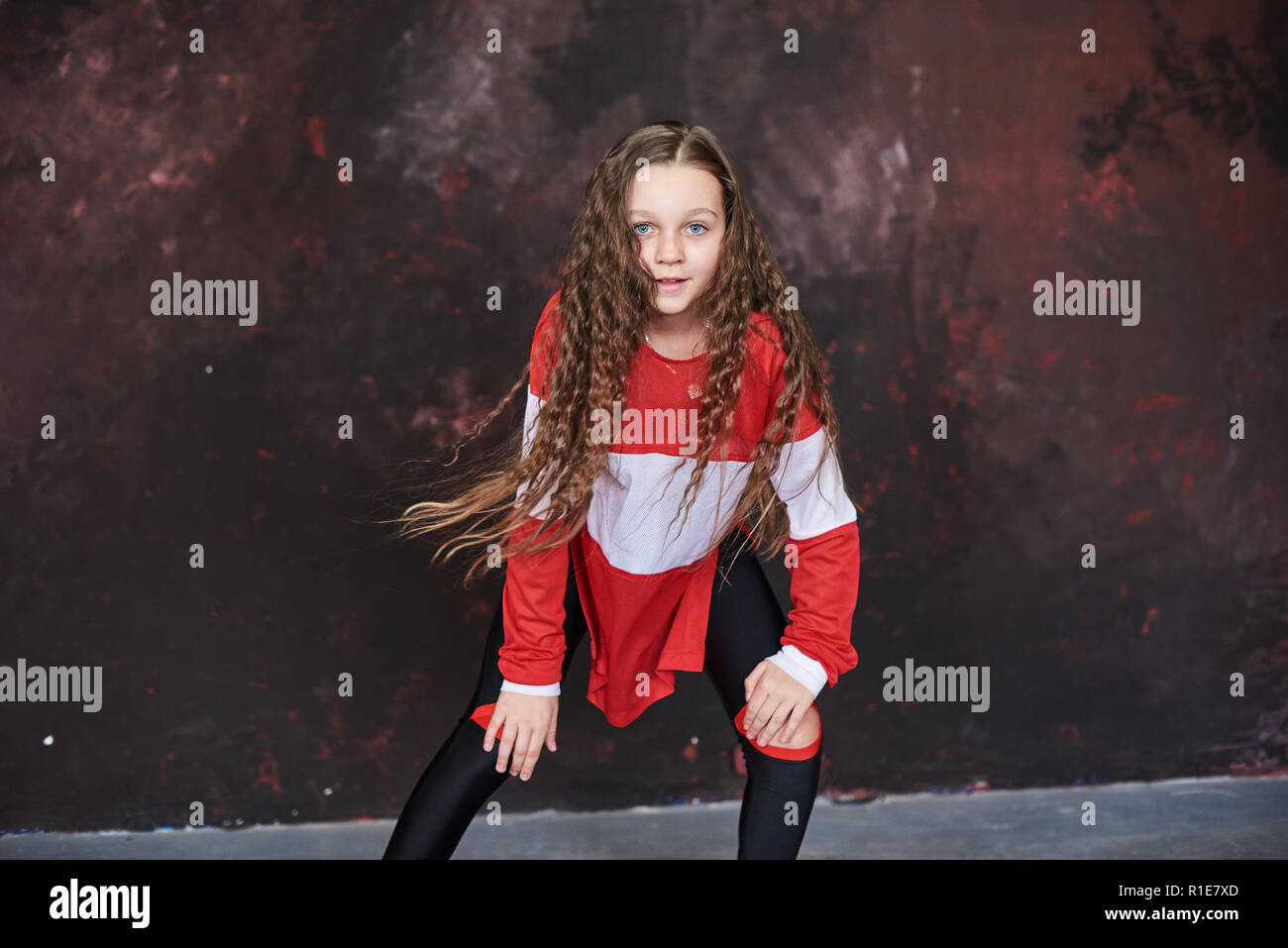 Young beautiful girl dancing in a trendy clothes on a grunge background ...