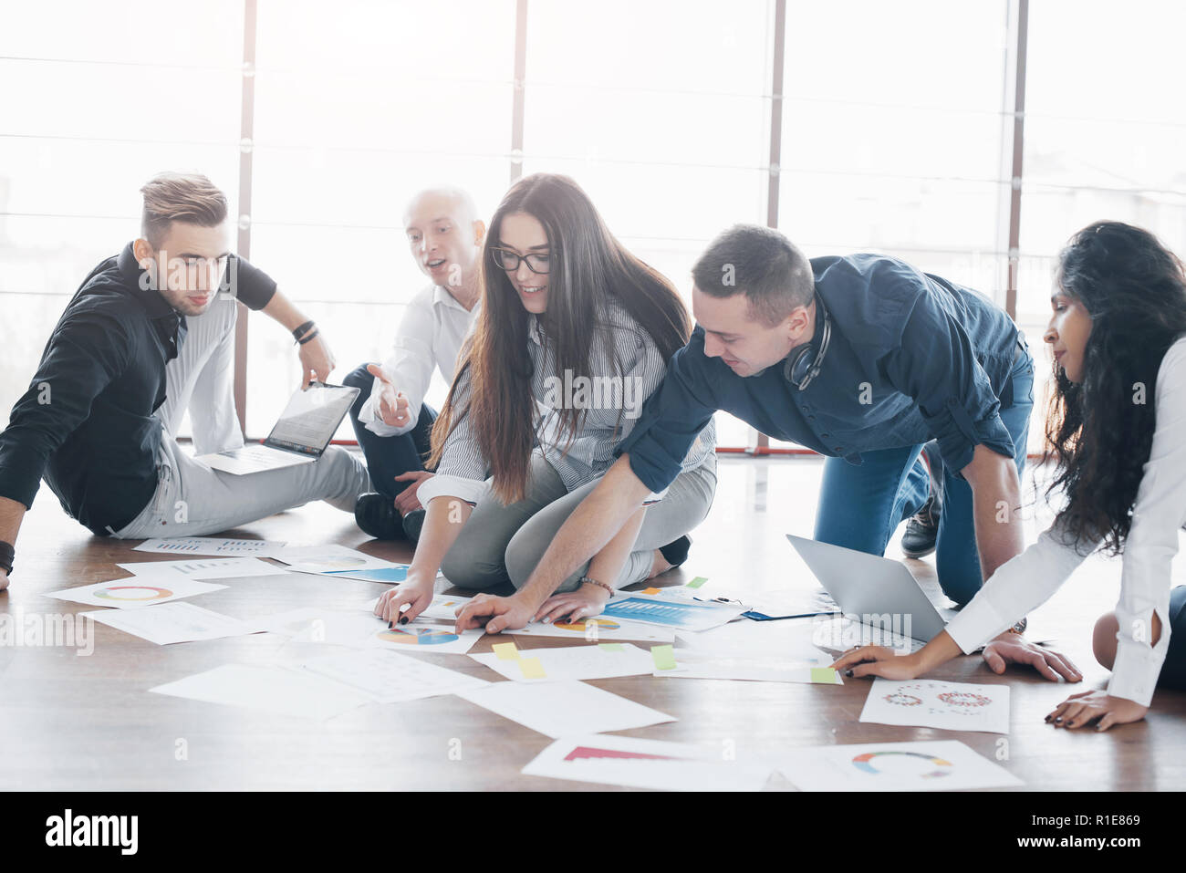 Planning strategy together. Business team looking at papers on floor ...