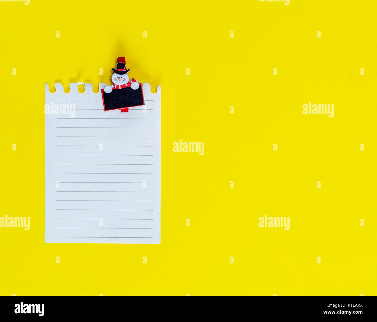 white blank sheet in a line torn out of notepad on a yellow background ...