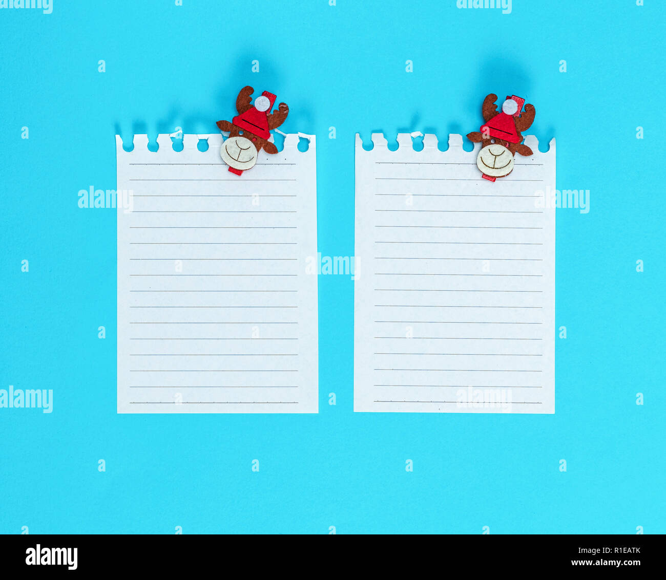 two white blank sheet in a line torn out of notepad on a blue ...
