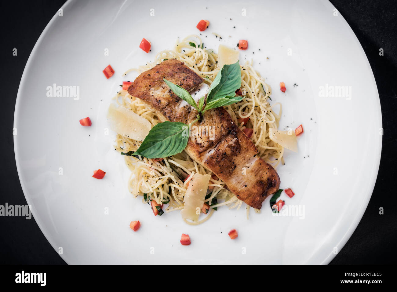 fresh cod fish fillet on mixed vegetable and parmesan spaghetti pasta ...