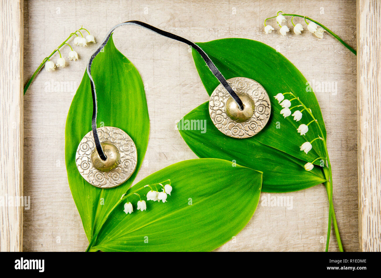 Spiritual silver Tibetan bells on wooden background with white spring ...