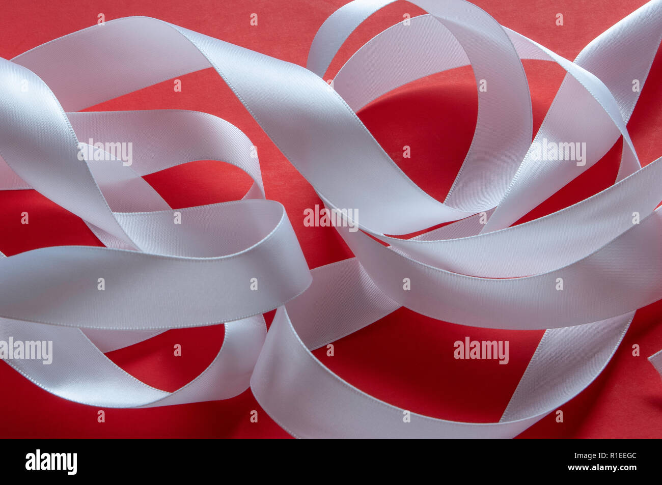 A continuous swirl of medium-width shiny white satin ribbon set against ...
