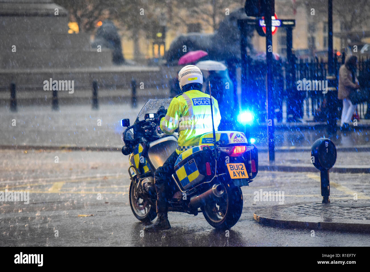 Police outrider motorcyclist stationary in heavy rain near Trafalgar ...