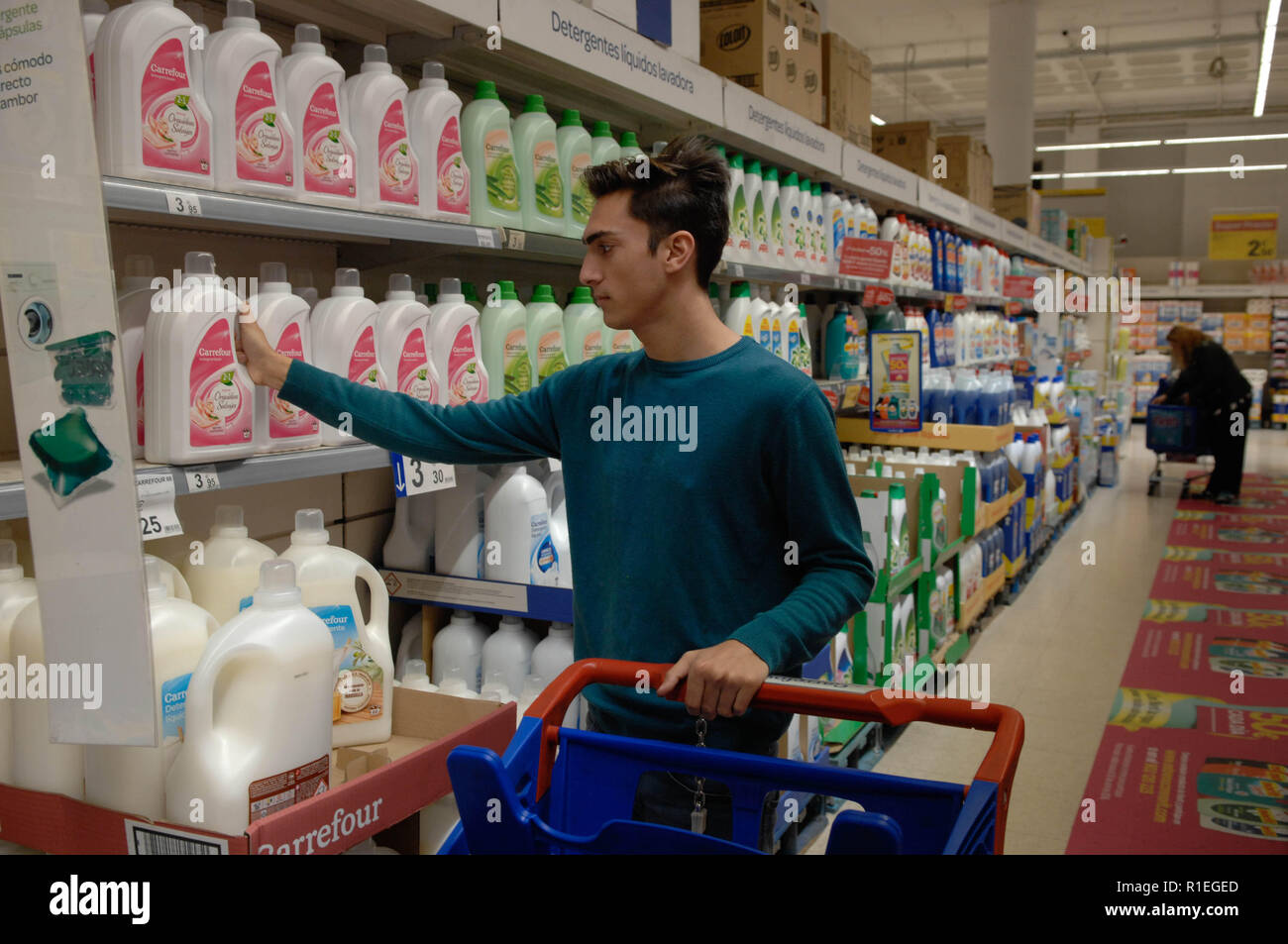 a customer picking up a bottle of Carrefour detergent Stock Photo - Alamy