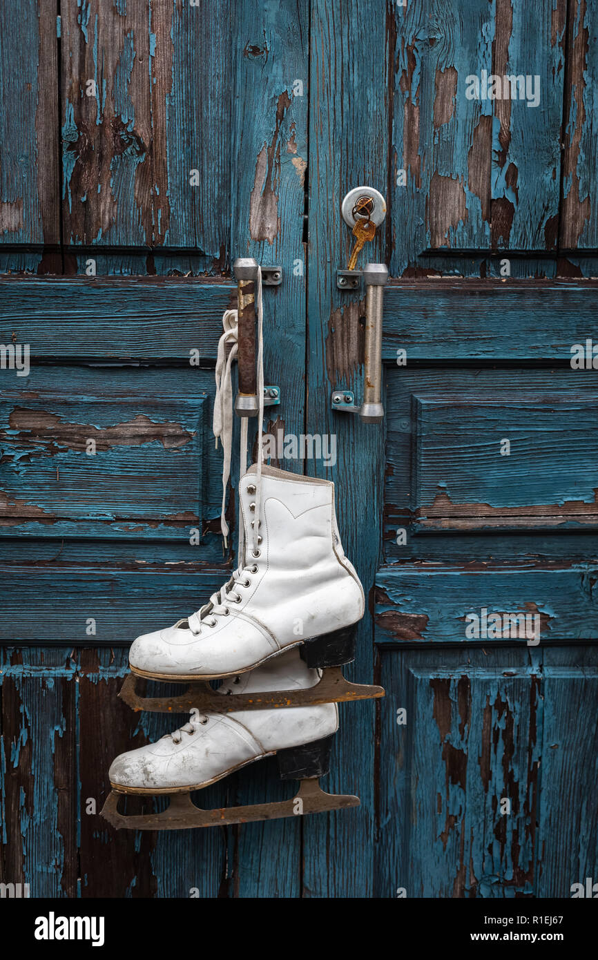 Pair of vintage white Ice Skates hanging on the blue rustic door, toned ...
