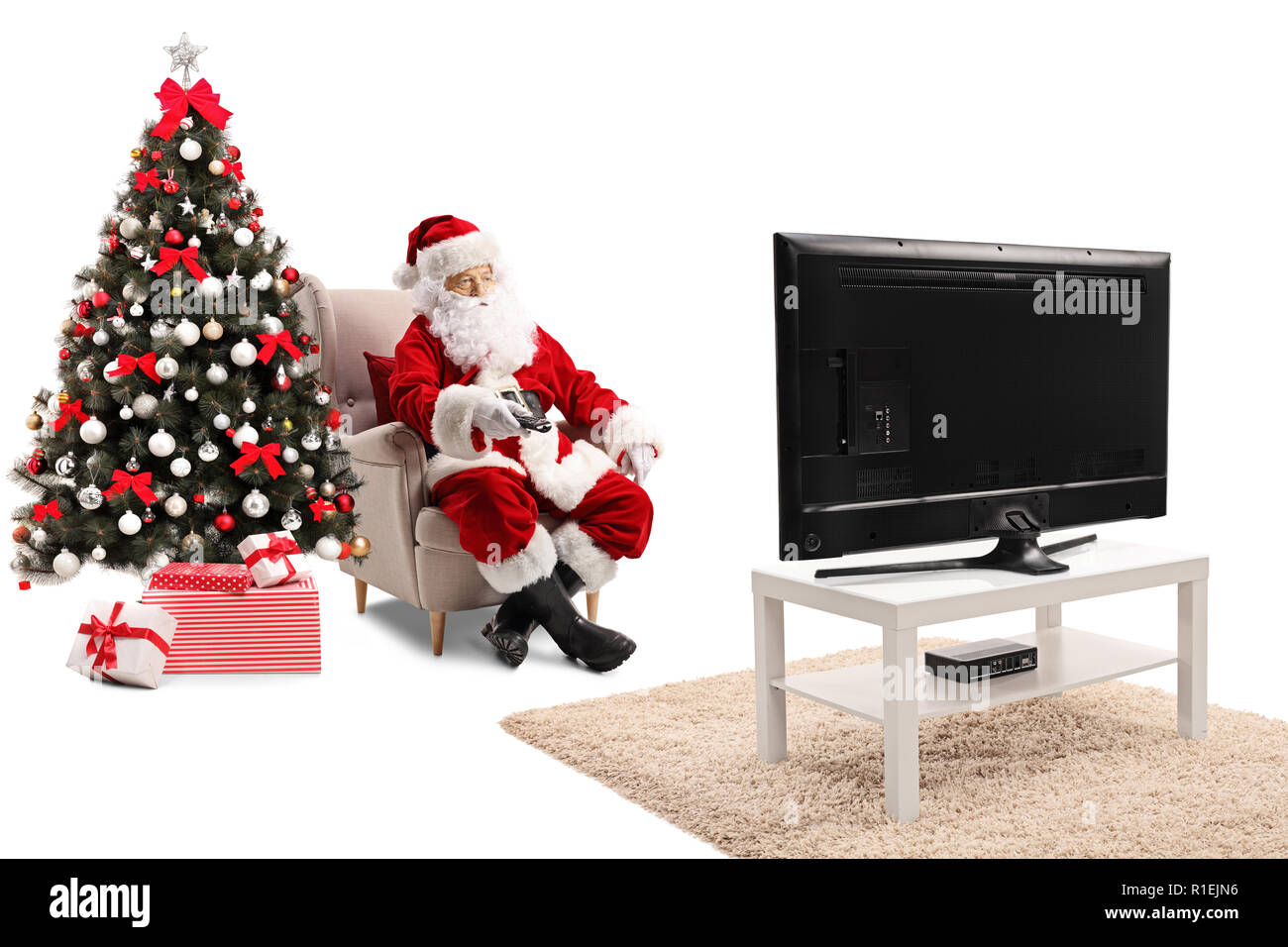 Santa Claus sitting in an armchair, holding a remote controller and ...
