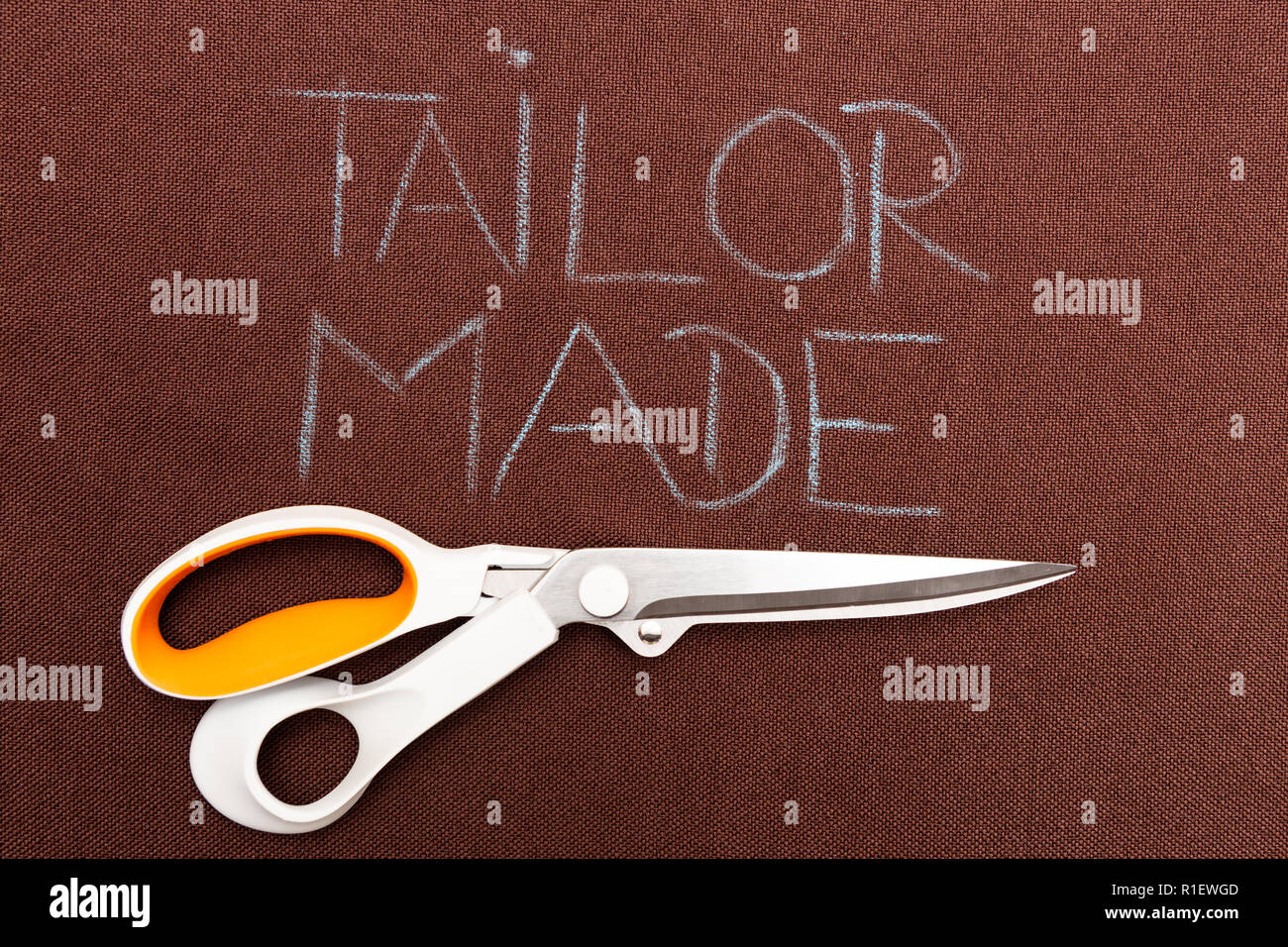 Scissors underlining tailor made text on brown fabric as background ...