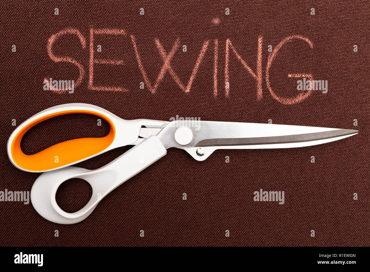 Sewing text on brown material background underlined with pair of ...